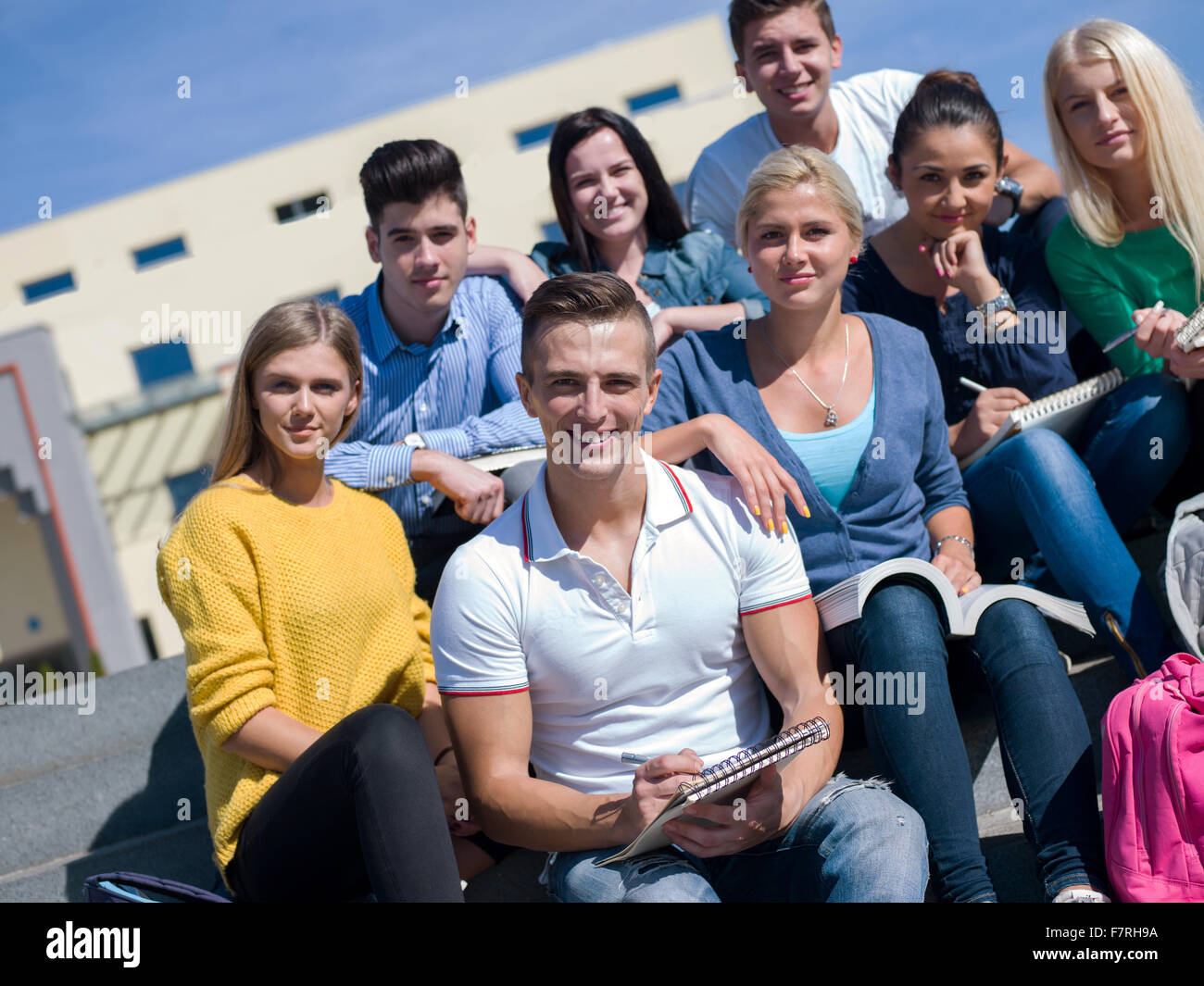 Group portrait of happy students outside sitting on steps have fun ...