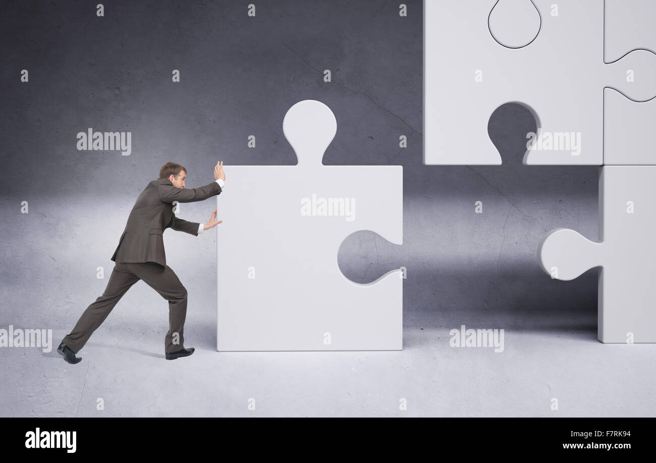 Businessman pushing grey puzzle piece Stock Photo - Alamy
