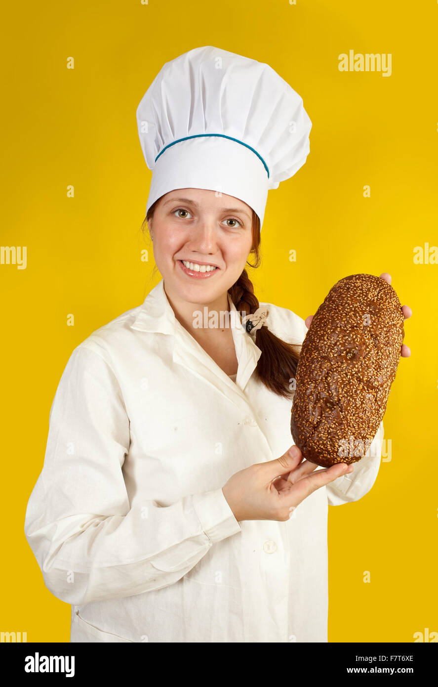 female baker is holding fresh bread over yellow Stock Photo - Alamy