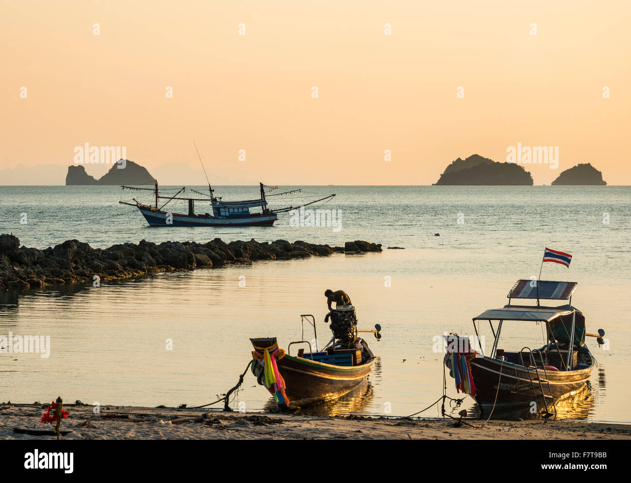 Boats on the beach in the sea at sunset, small islands in the distance ...