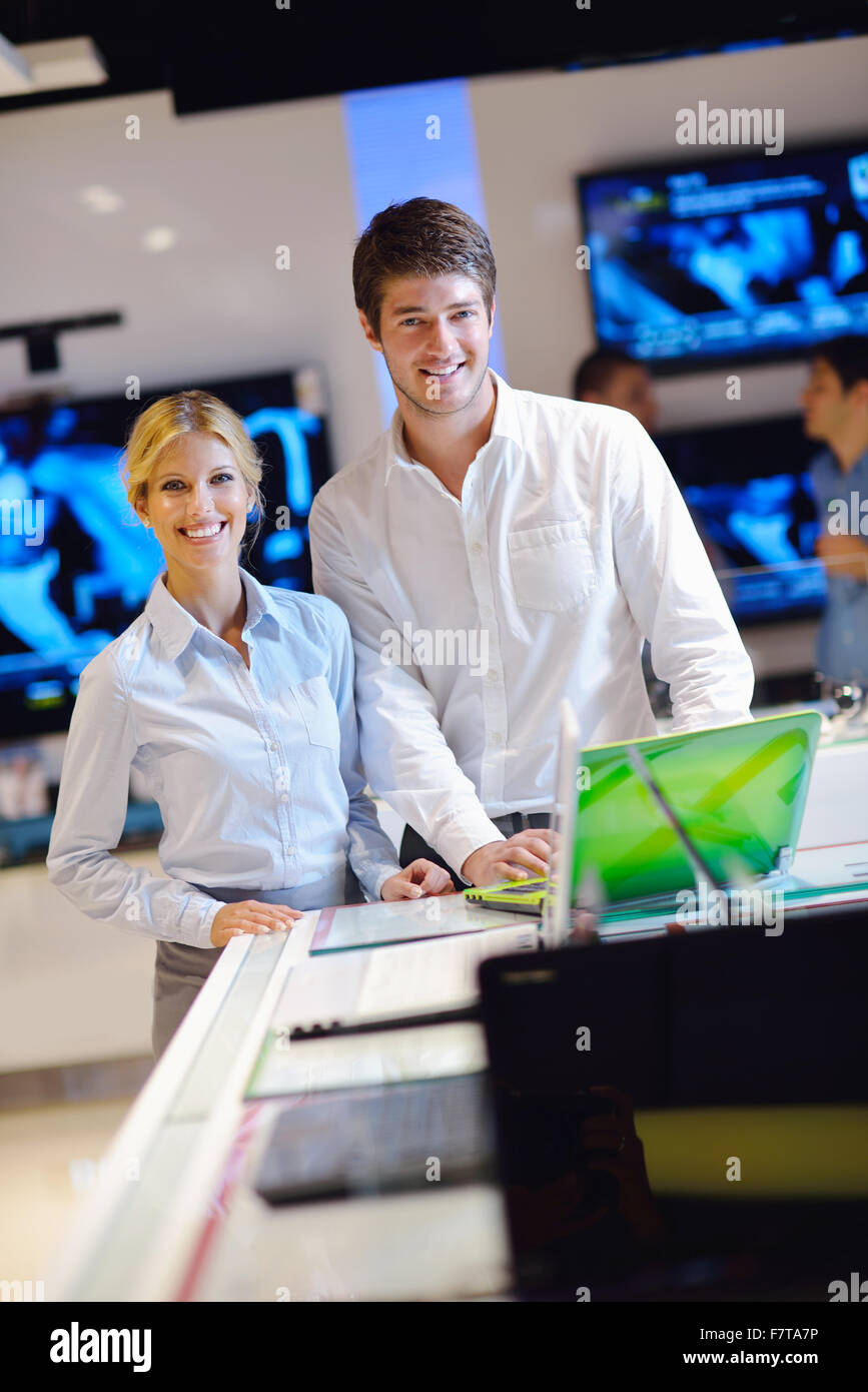 people in consumer electronics retail store looking at latest laptop ...