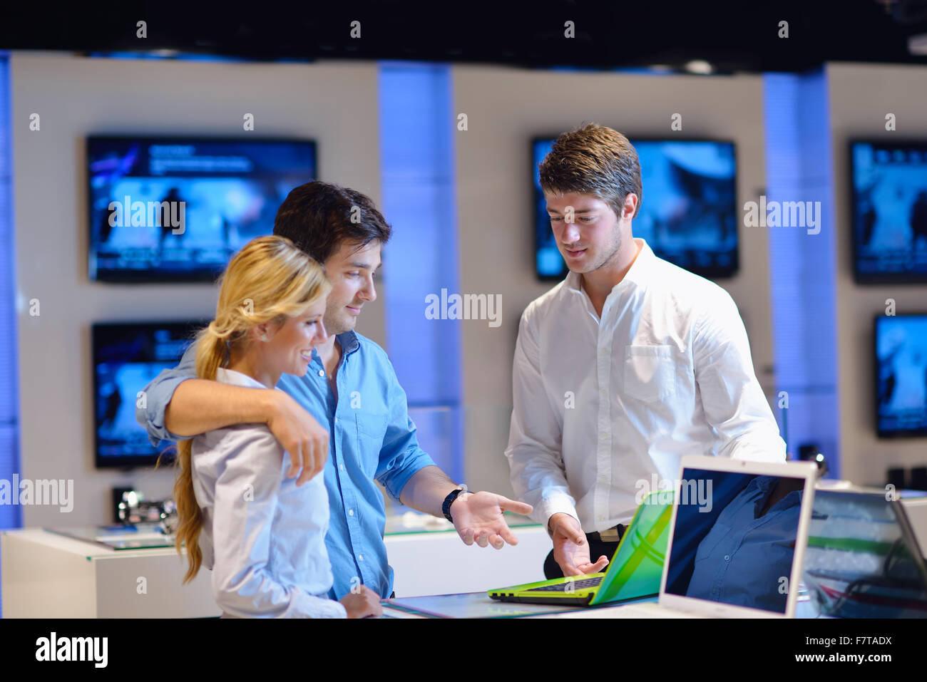 people in consumer electronics retail store looking at latest laptop ...