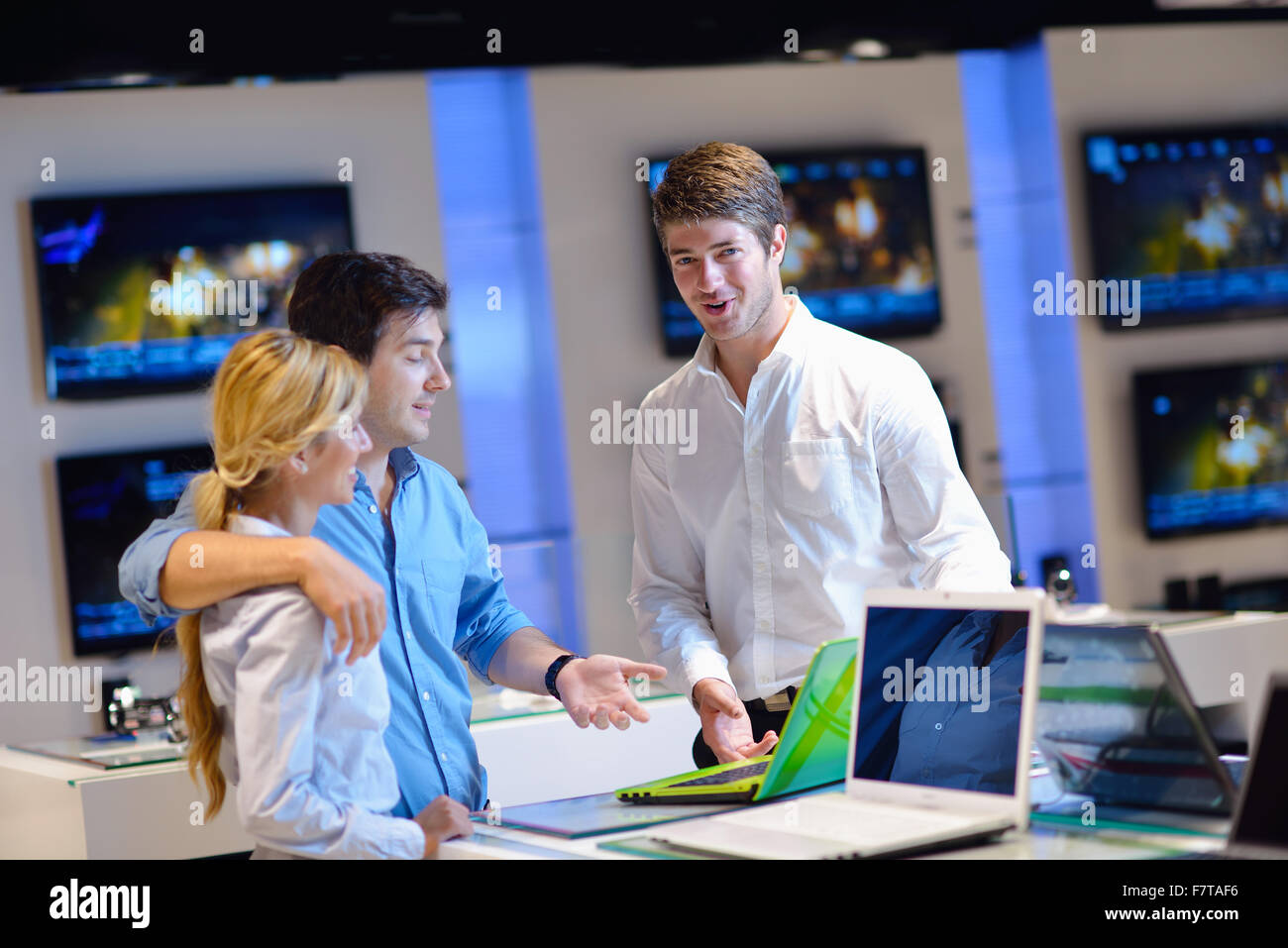 people in consumer electronics retail store looking at latest laptop ...
