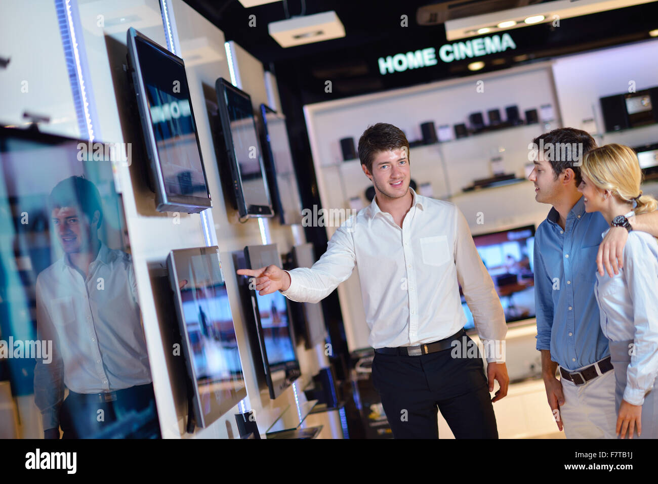 people in consumer electronics retail store looking at latest laptop ...