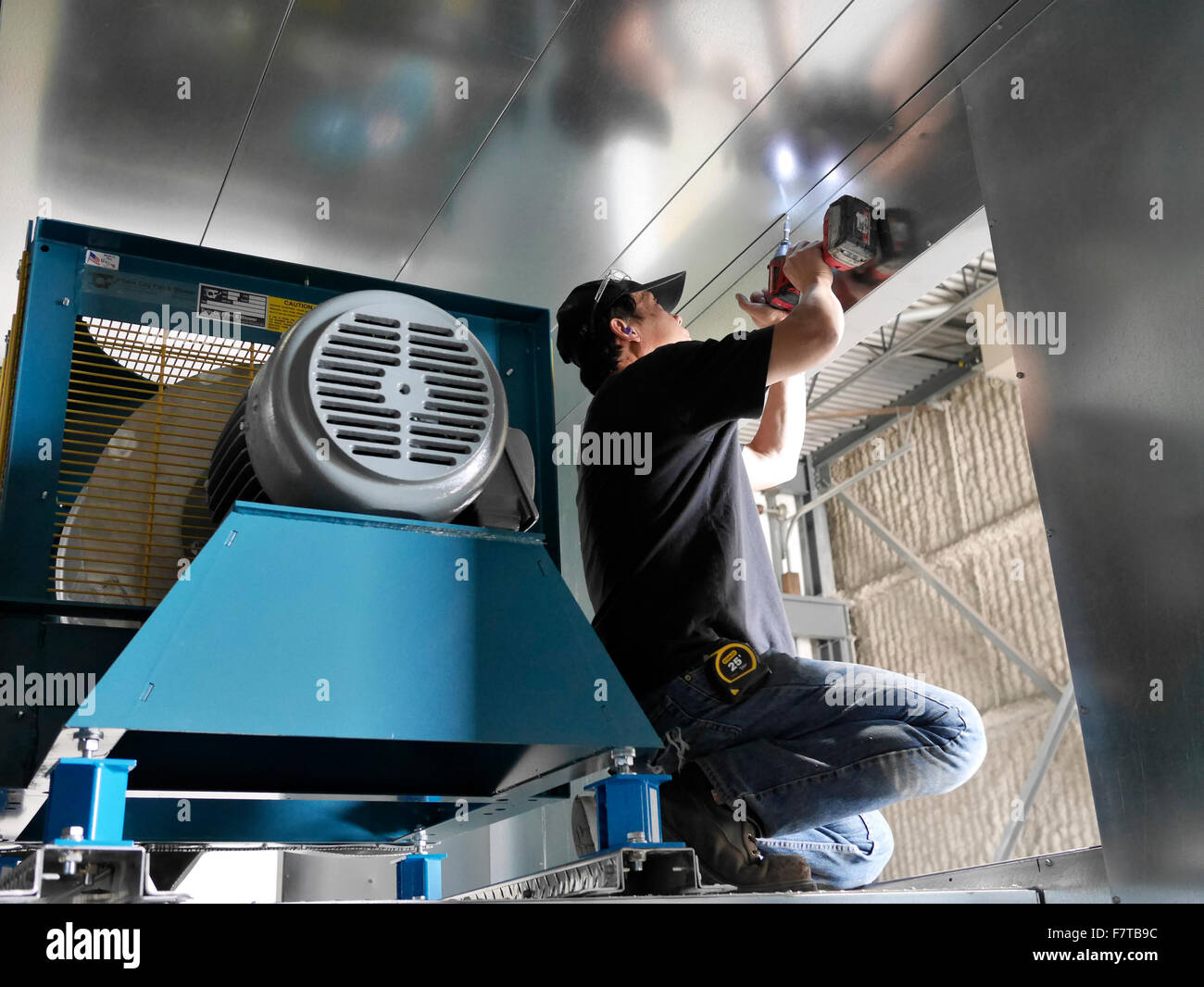 Worker assembling an industrial HVAC (heating, ventilating, and air ...