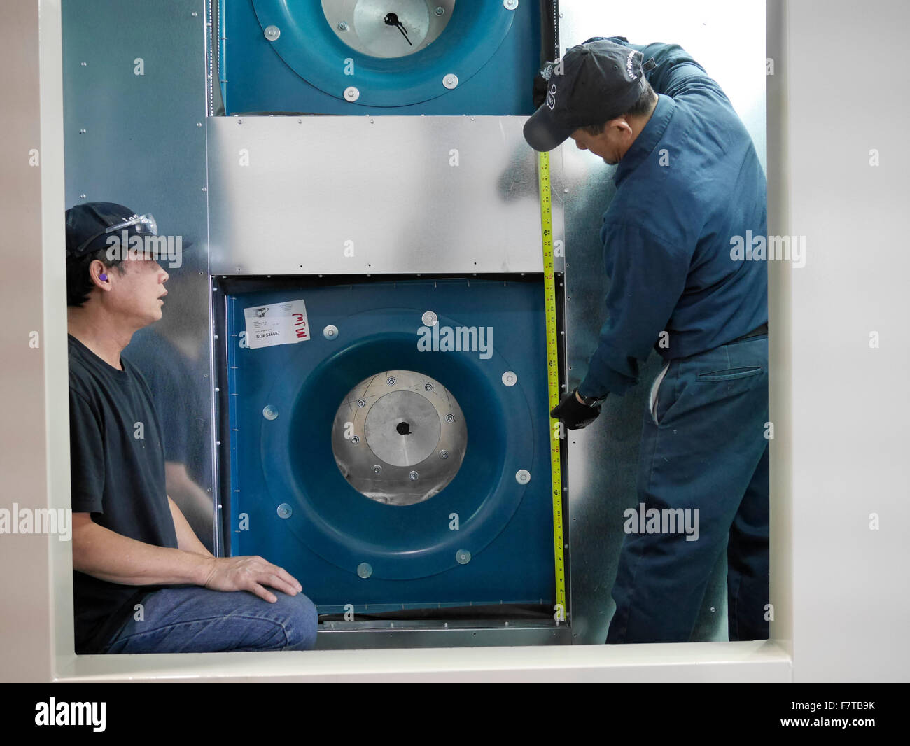 Two workers measuring HVAC fan unit Stock Photo - Alamy