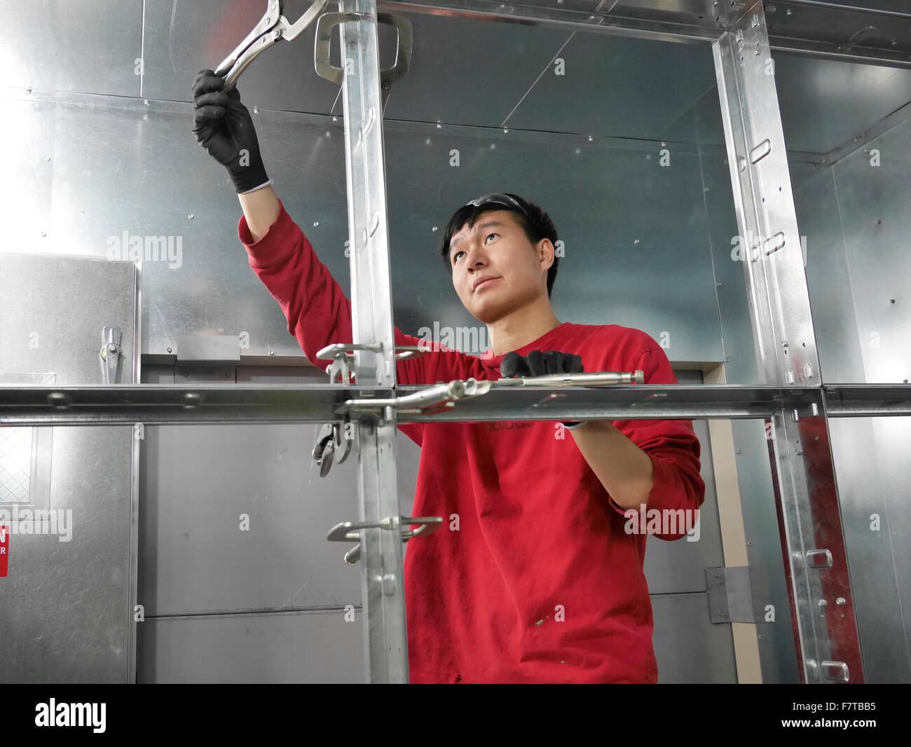 Worker fixing clamps to metal grid framework Stock Photo - Alamy