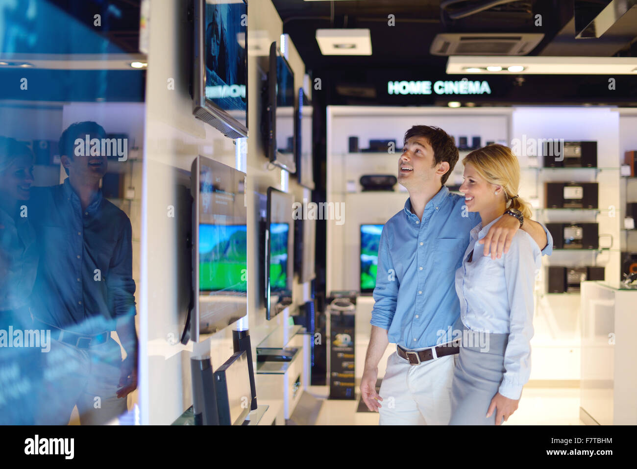 people in consumer electronics retail store looking at latest laptop ...