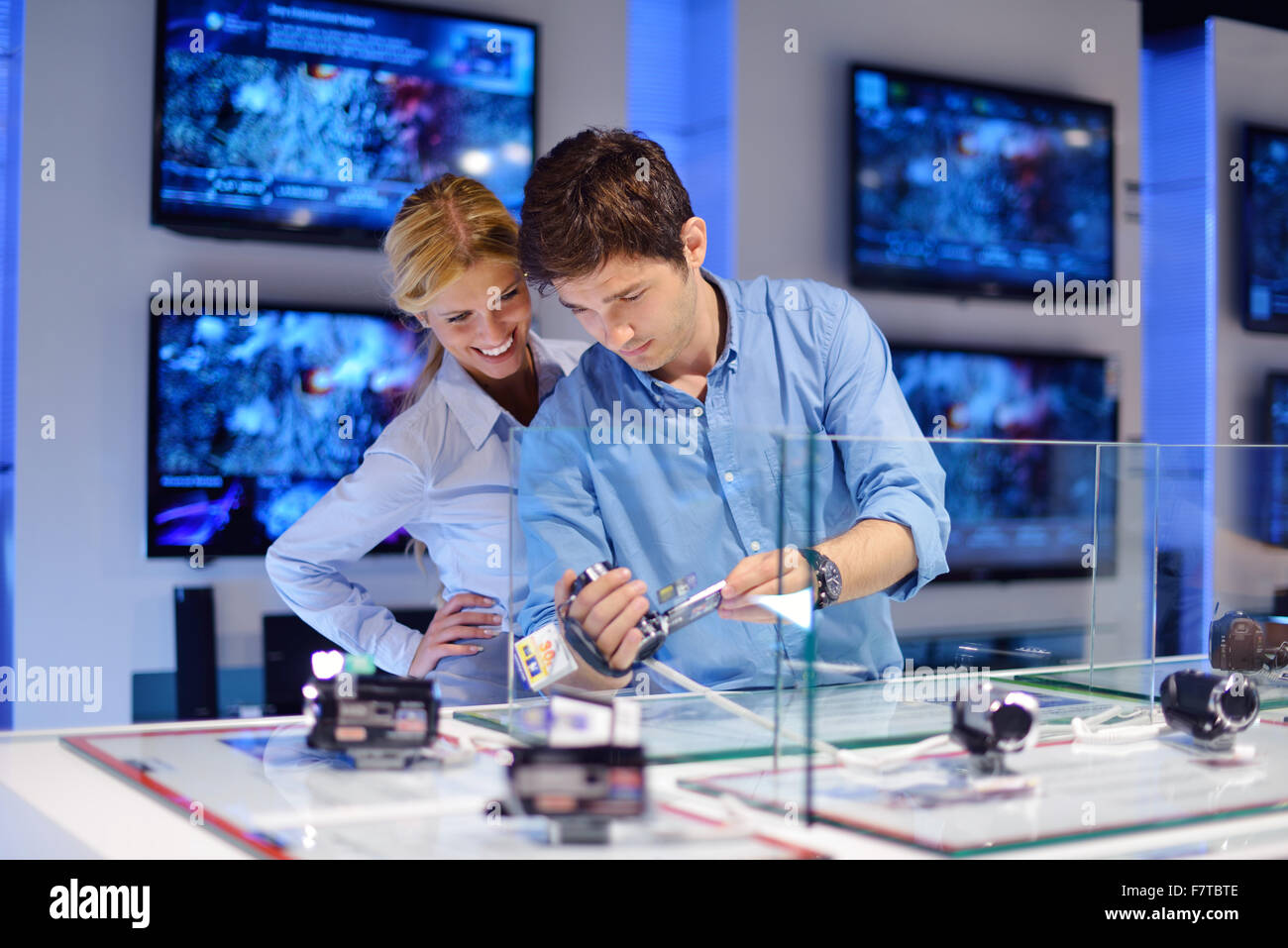 people in consumer electronics retail store looking at latest laptop ...