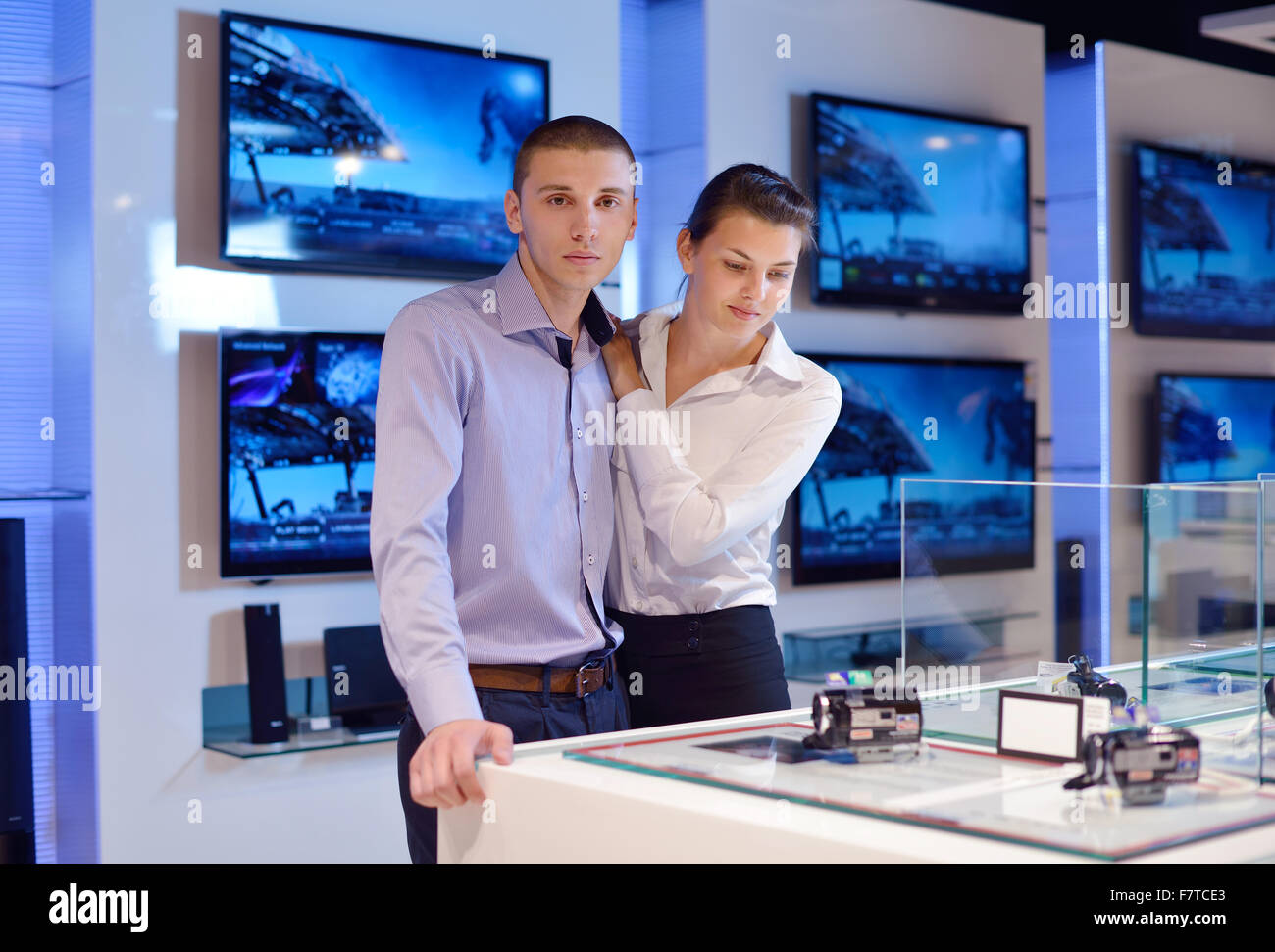 people in consumer electronics retail store looking at latest laptop ...