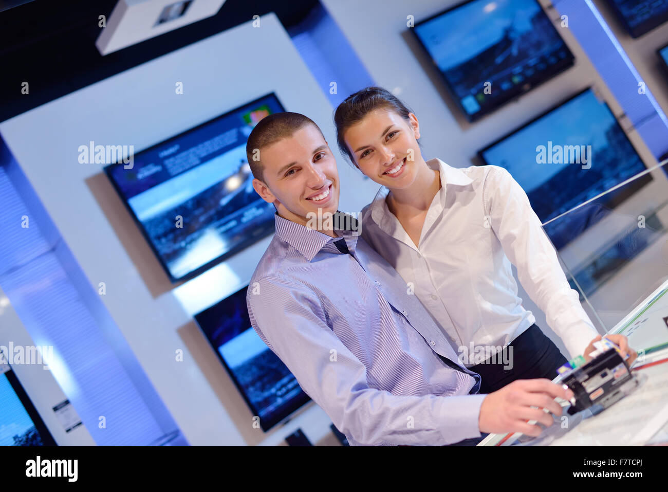 people in consumer electronics retail store looking at latest laptop ...
