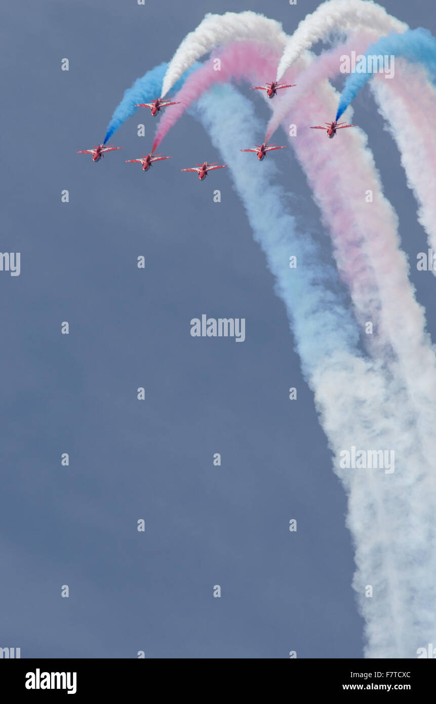 Seven RAF Red Arrows perform an acrobatic maneuver in formation with ...