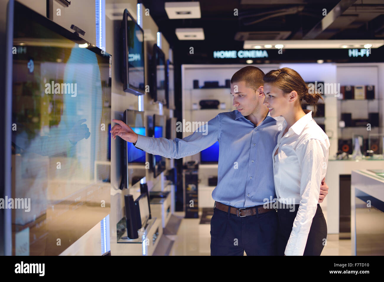 people in consumer electronics retail store looking at latest laptop ...