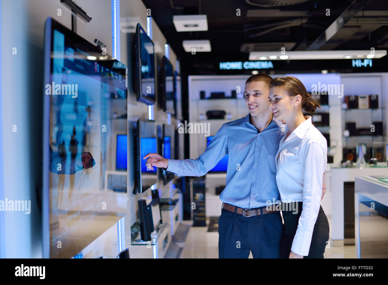 Young couple in consumer electronics store looking at latest laptop ...