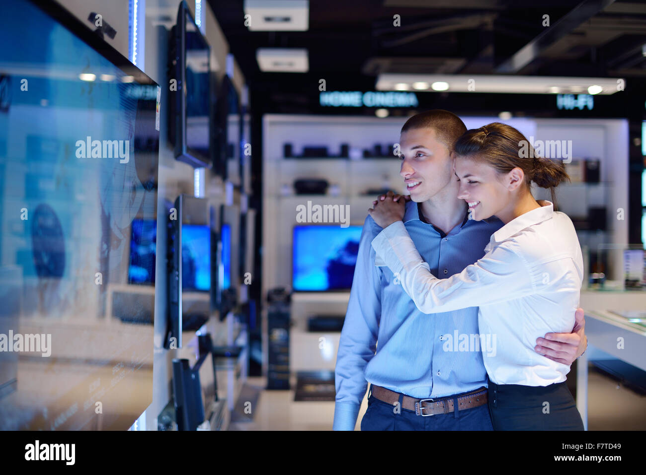 people in consumer electronics retail store looking at latest laptop ...