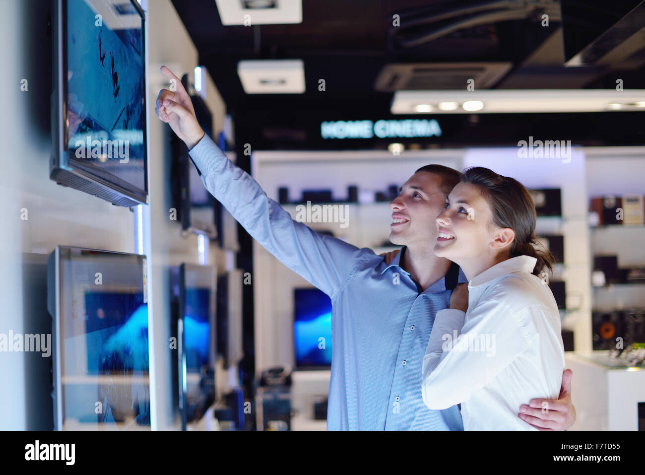 people in consumer electronics retail store looking at latest laptop ...