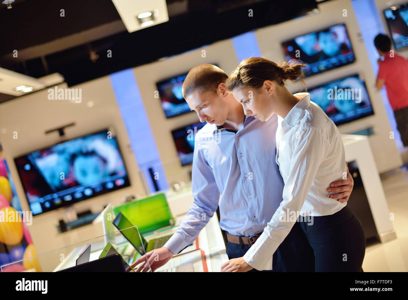 people in consumer electronics retail store looking at latest laptop ...