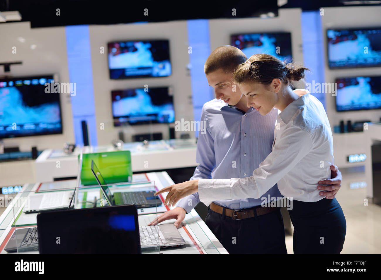 Young couple in consumer electronics store looking at latest laptop ...