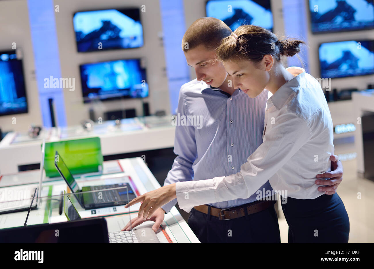 people in consumer electronics retail store looking at latest laptop ...