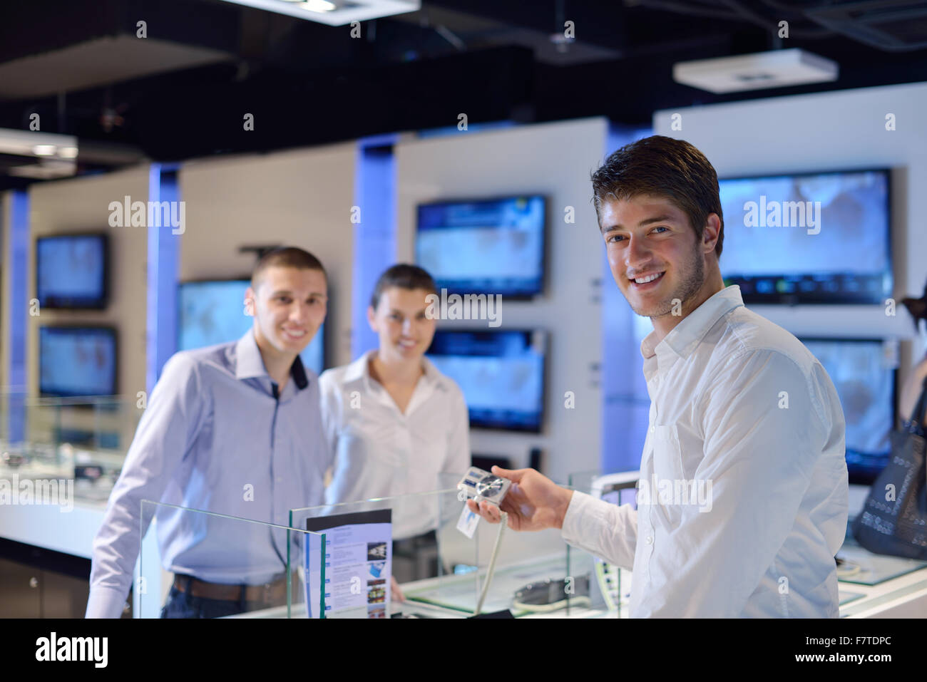 people in consumer electronics retail store looking at latest laptop ...