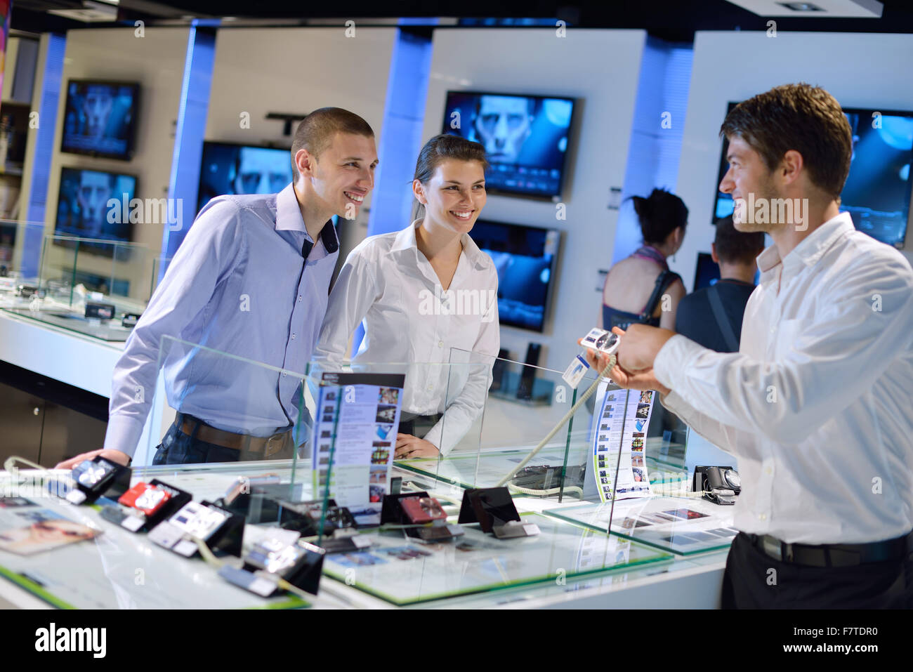 Young couple in consumer electronics store looking at latest laptop ...