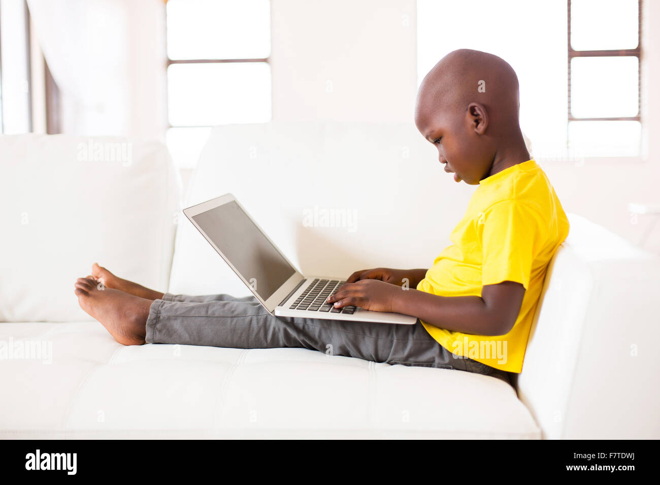 side view of cute little black boy using laptop at home Stock Photo - Alamy