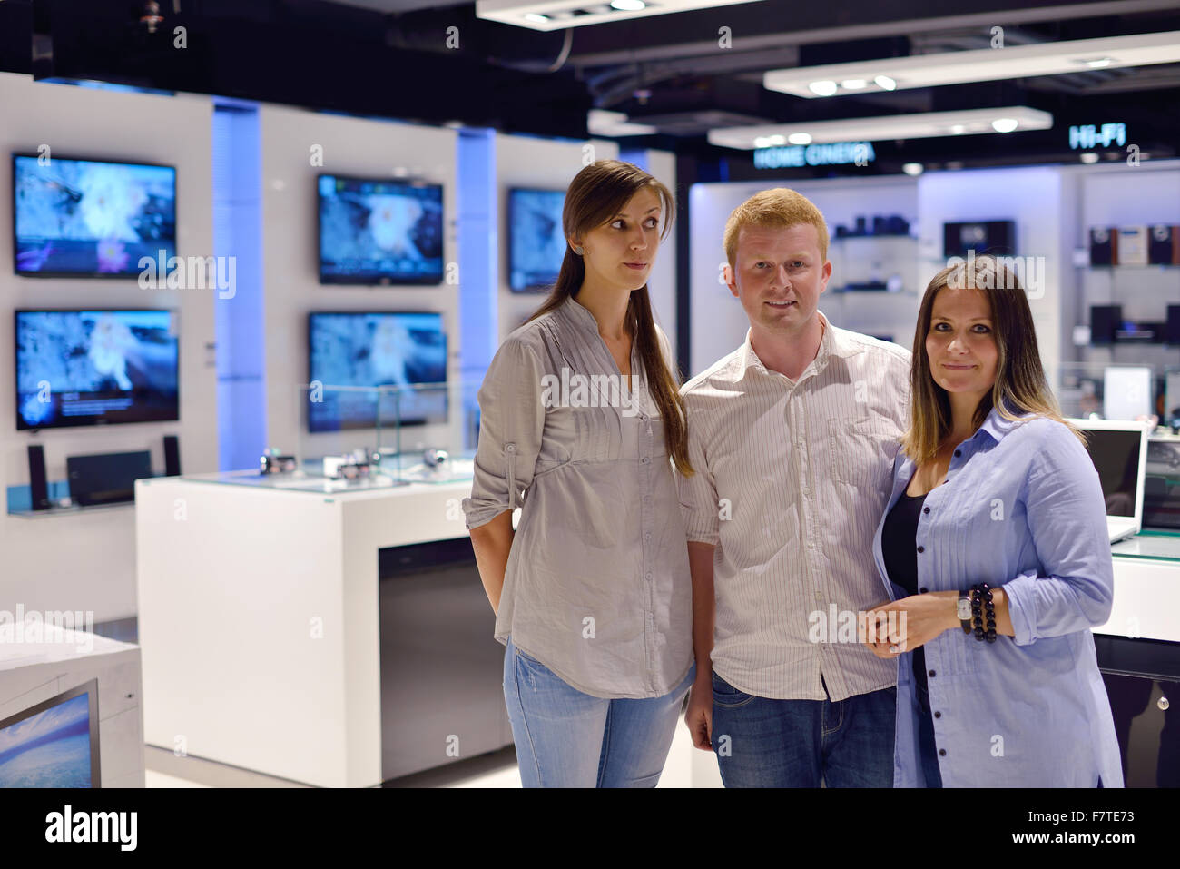 people in consumer electronics retail store looking at latest laptop ...