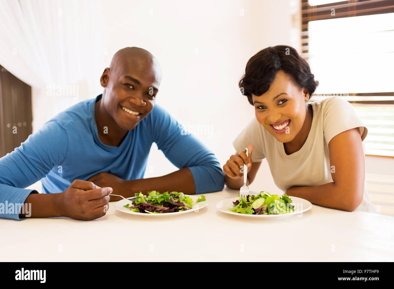 portrait of young African American couple eating healthy salad for ...