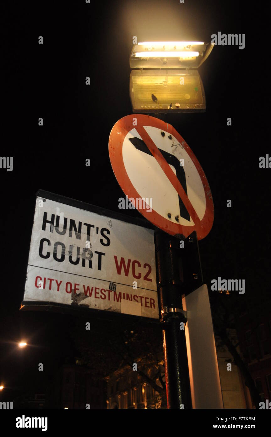 A street sign and road sign attached to a street lamp which is brightly ...