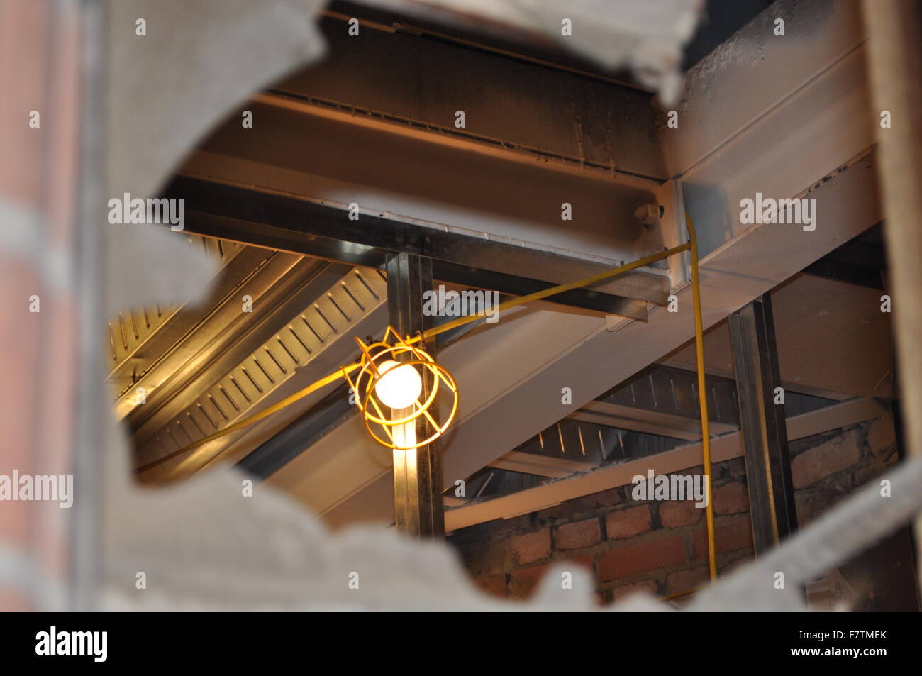A brightly lit light bulb shining through a smashed window Stock Photo ...