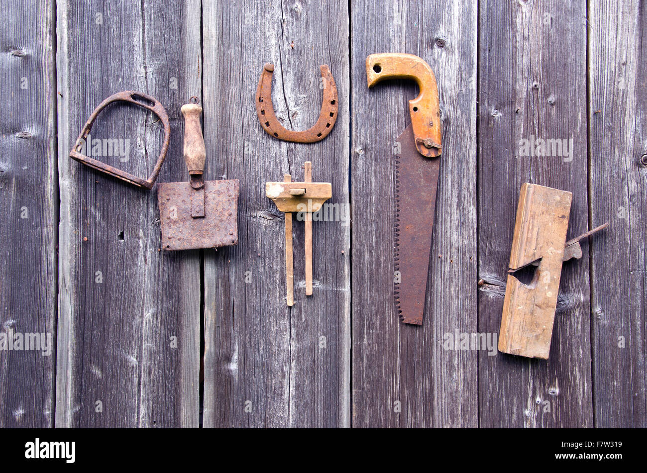 Old rusty tools hanging on grey wooden farm barn wall Stock Photo - Alamy