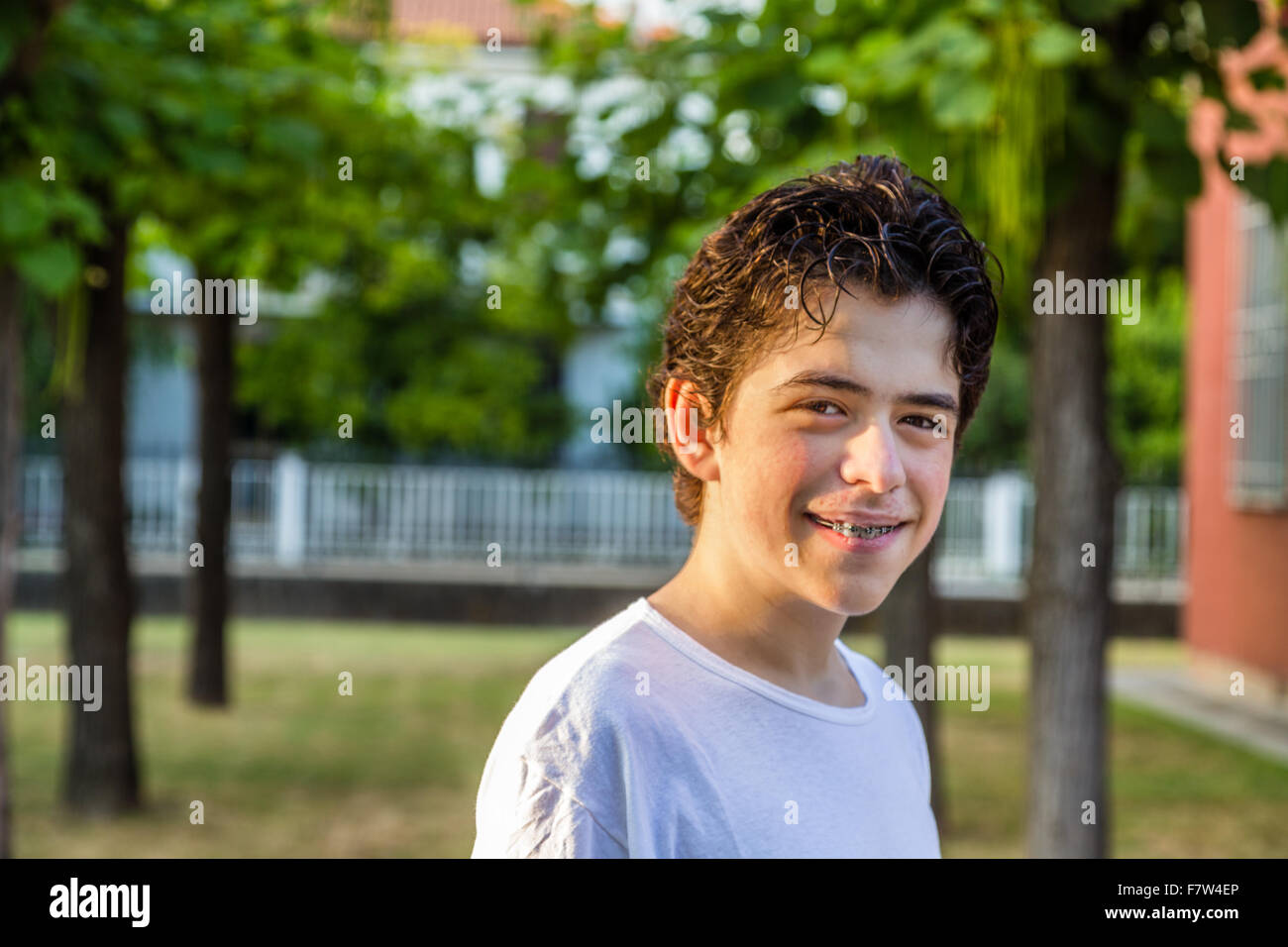 teenager with acne skin smiling while showing braces with trees in the ...