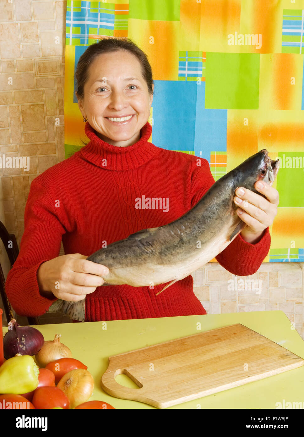 Mature woman with salmon fish in her kitchen Stock Photo - Alamy
