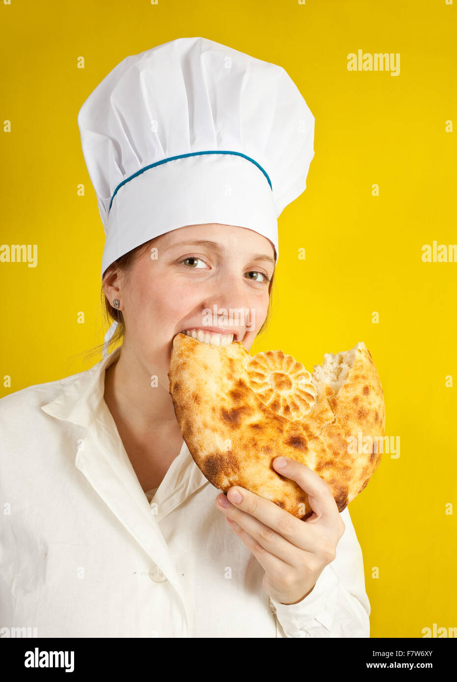 female baker is eating fresh loaf over yellow Stock Photo - Alamy