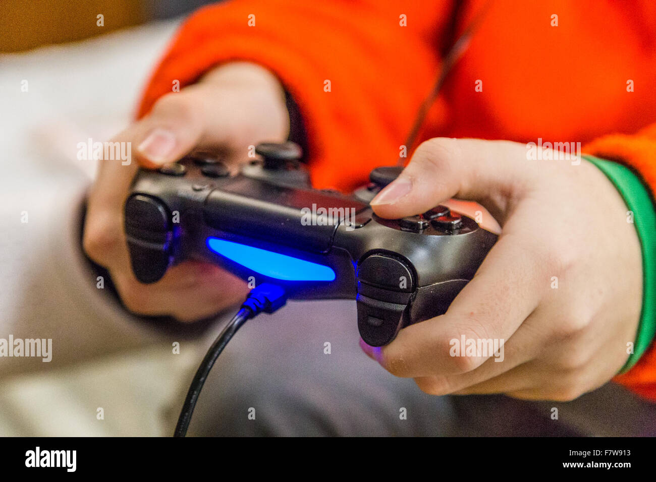 close detail of hands of boy playing videogames with a black wireless ...