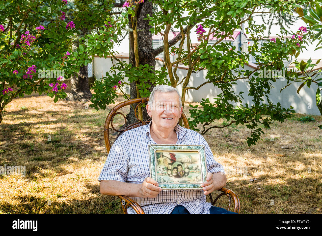 elderly octogenarian male smiling and showing old vintage photo in a ...