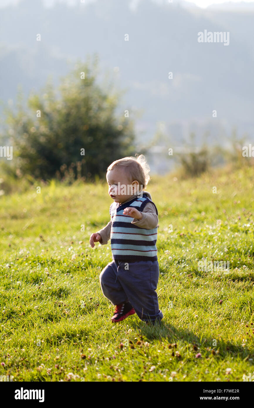 Portrait of running baby on mountains background at sunset Stock Photo ...