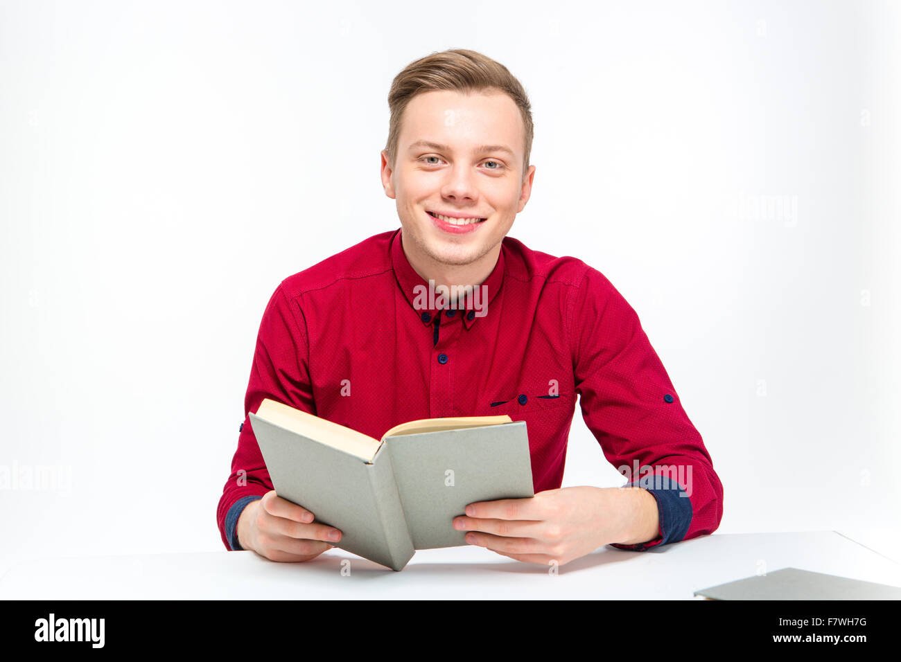 Happy smiling handsome man in red shirt sitting and reading book over ...