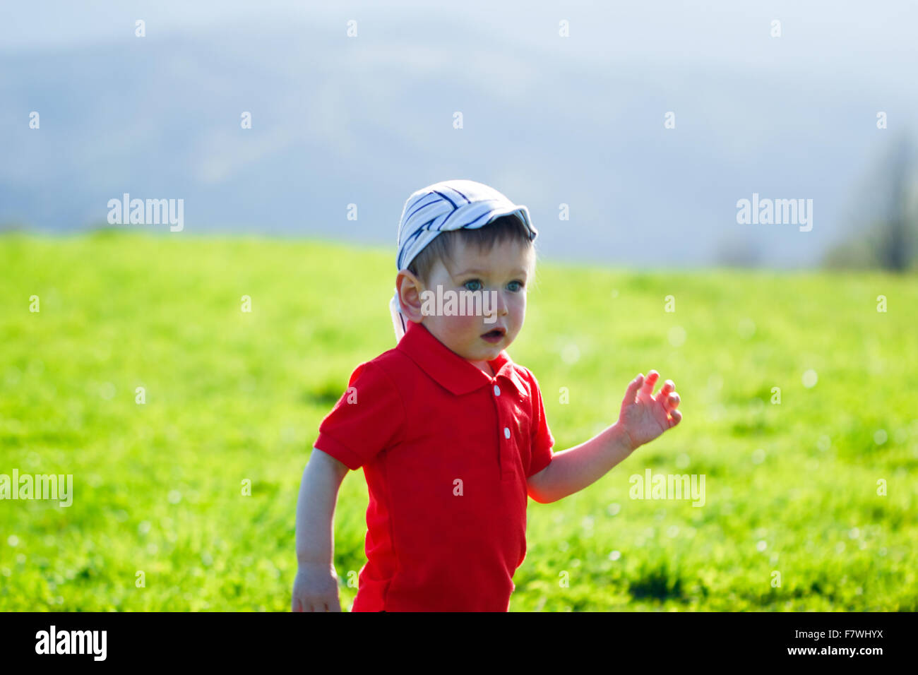 Running baby boy in mountains on grass background Stock Photo - Alamy