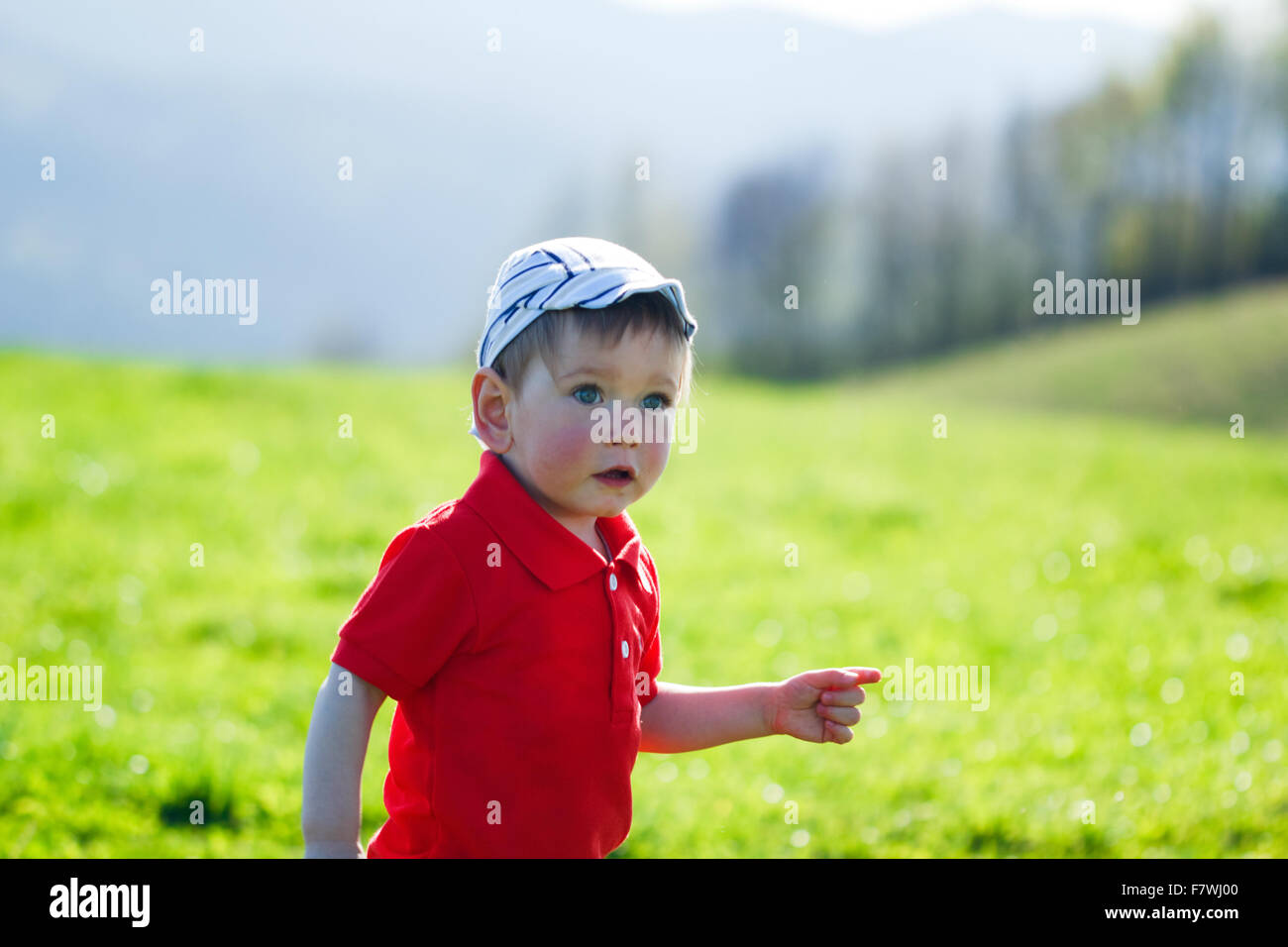 Running baby boy in mountains on grass background Stock Photo - Alamy