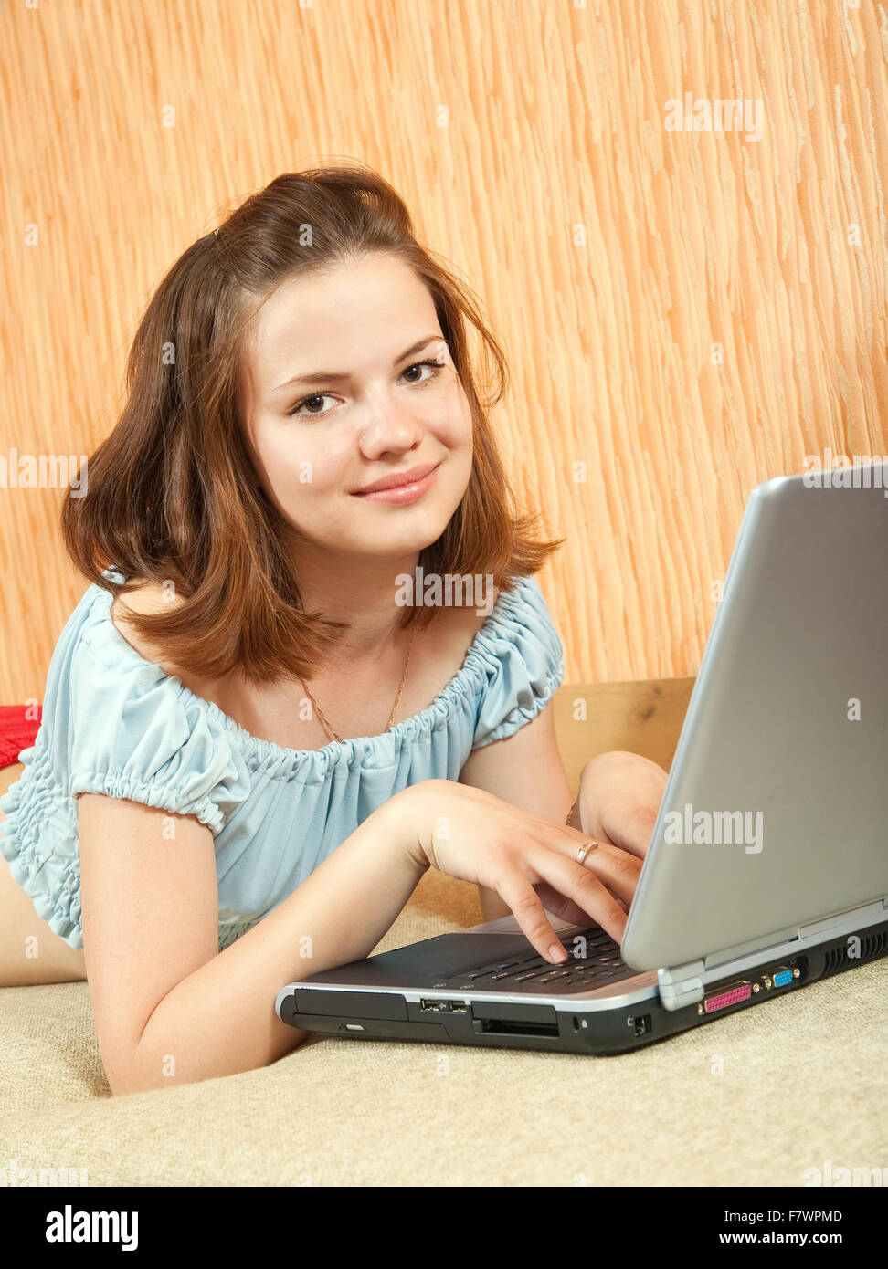 Relaxed girl lying on sofa in livingroom with laptop Stock Photo - Alamy