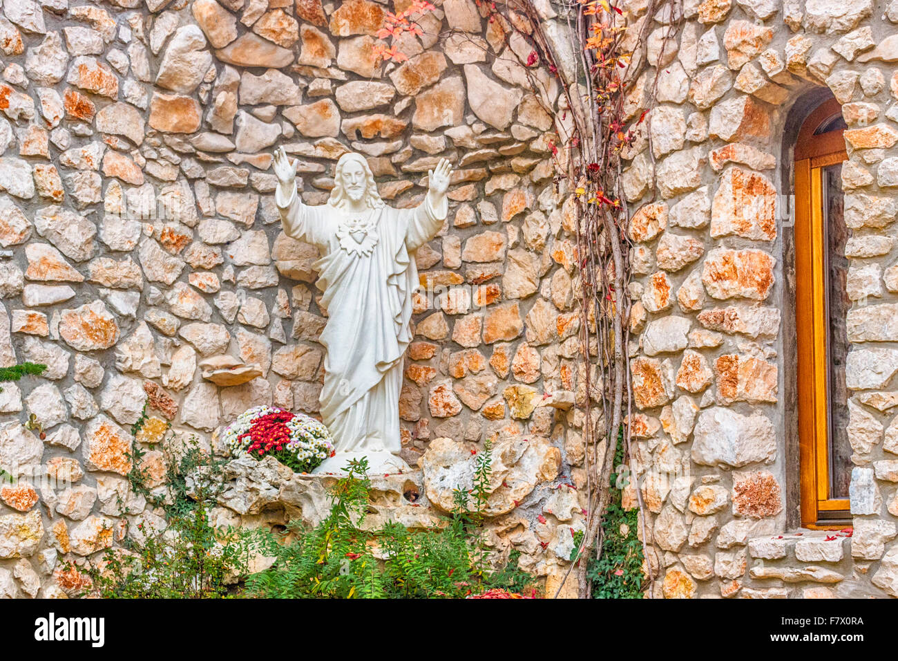 Sacred Heart of Jesus white statue in front of brick stone walls Stock ...