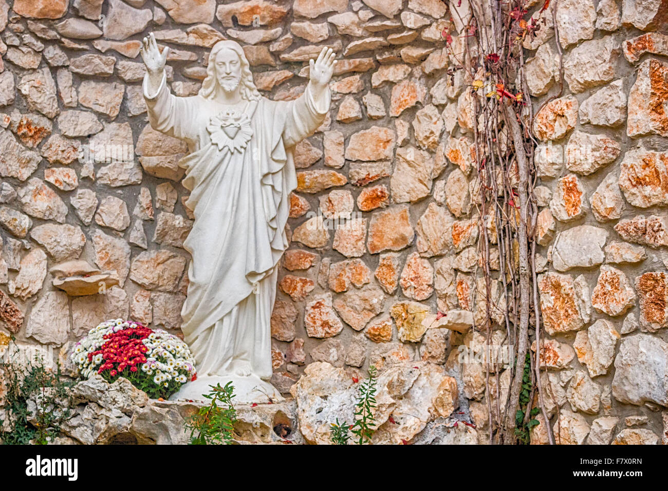 Sacred Heart of Jesus white statue in front of brick stone walls Stock ...