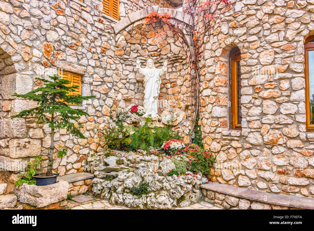 Sacred Heart of Jesus white statue in front of brick stone walls Stock ...
