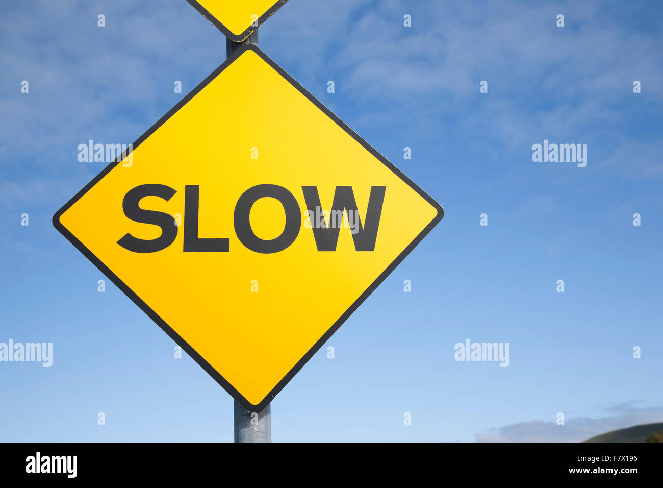 Yellow Slow Sign against Blue Sky Background Stock Photo - Alamy