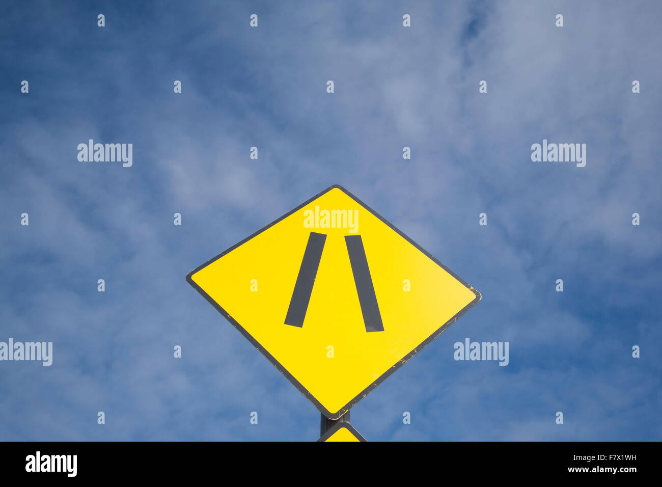 Road Narrowing Sign against Blue Sky Background Stock Photo - Alamy