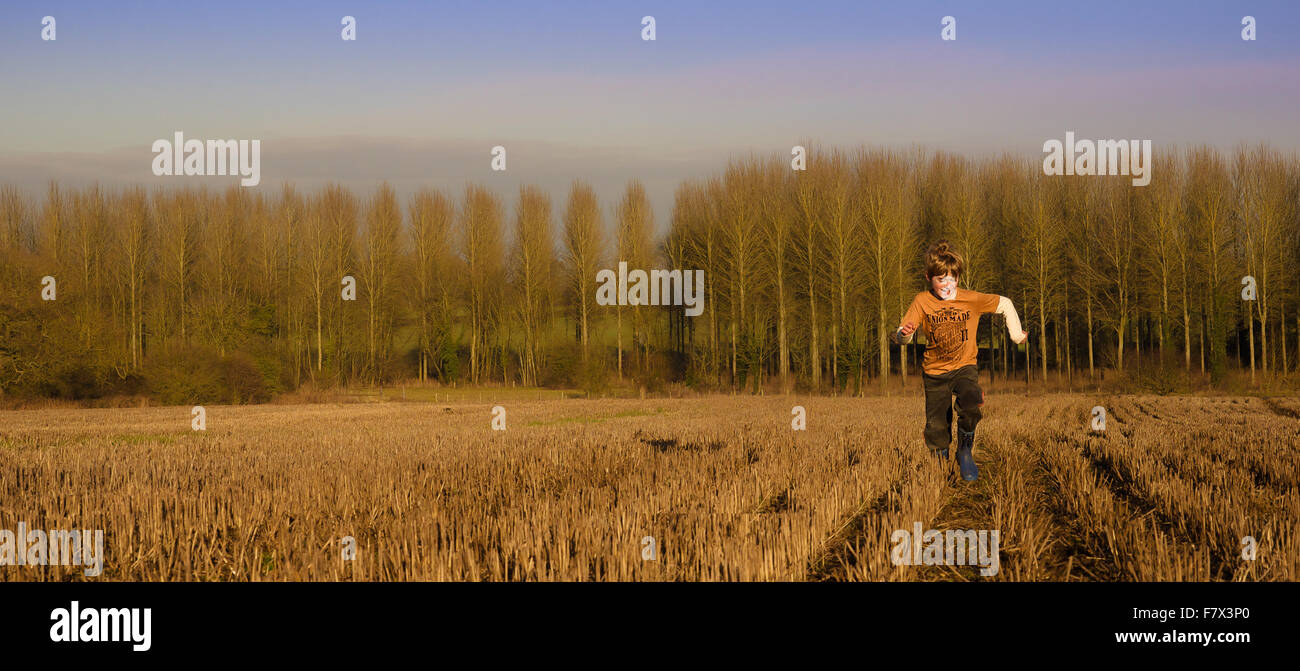 Boy running through a tree lined field hi-res stock photography and ...