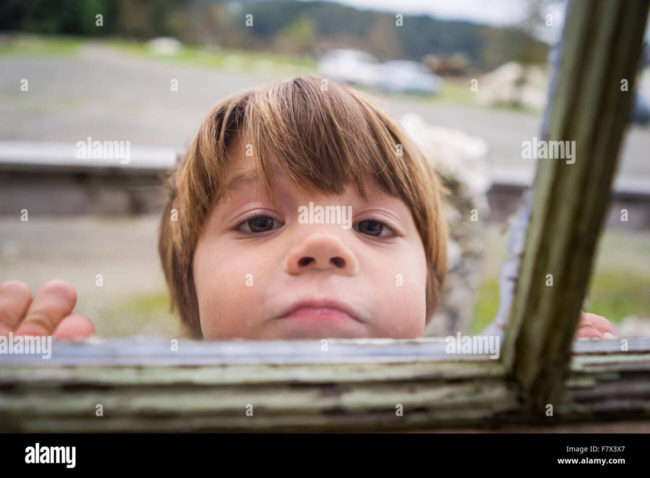 Boy looking through a window Stock Photo - Alamy