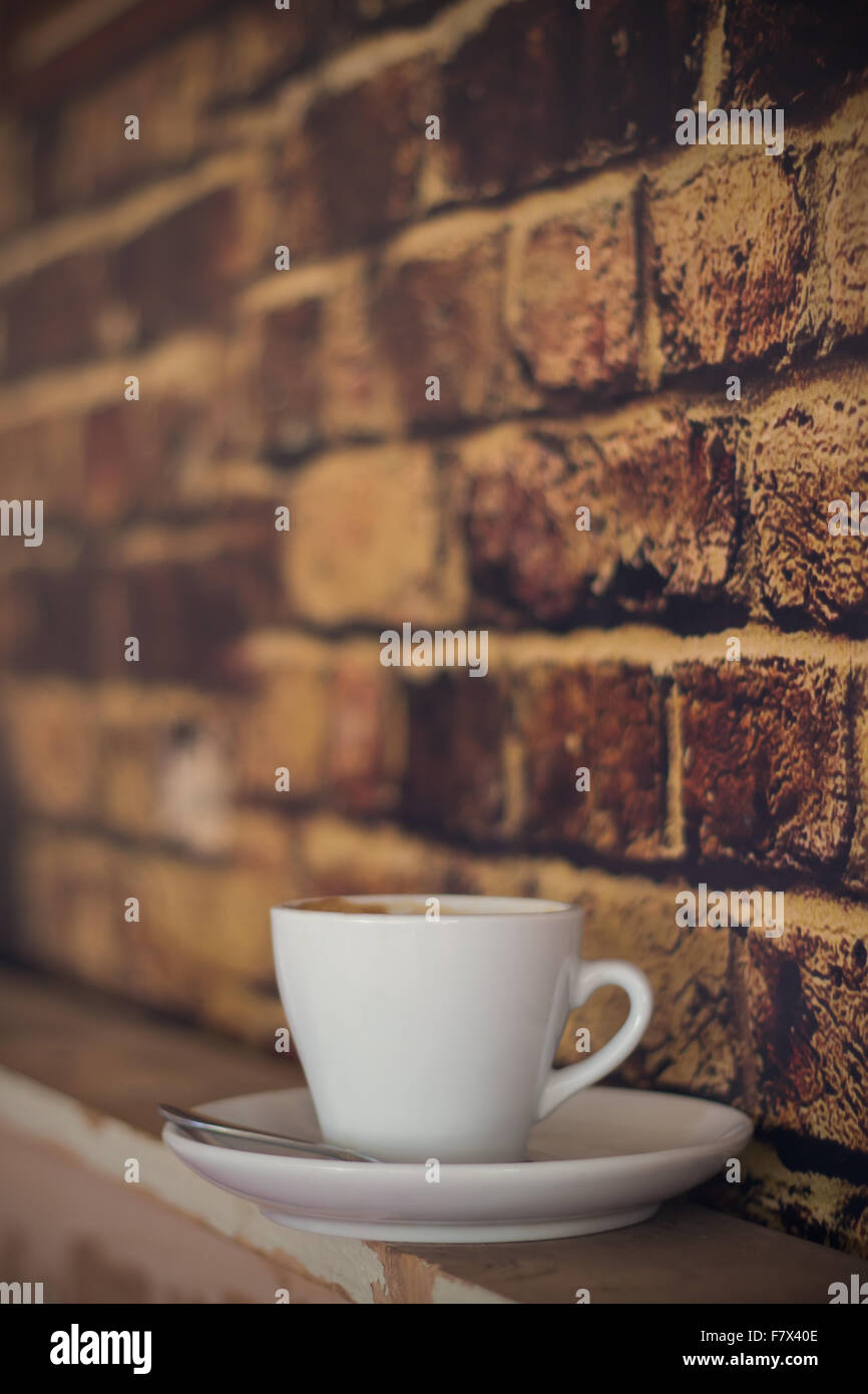 Cup of coffee by a brick wall Stock Photo - Alamy