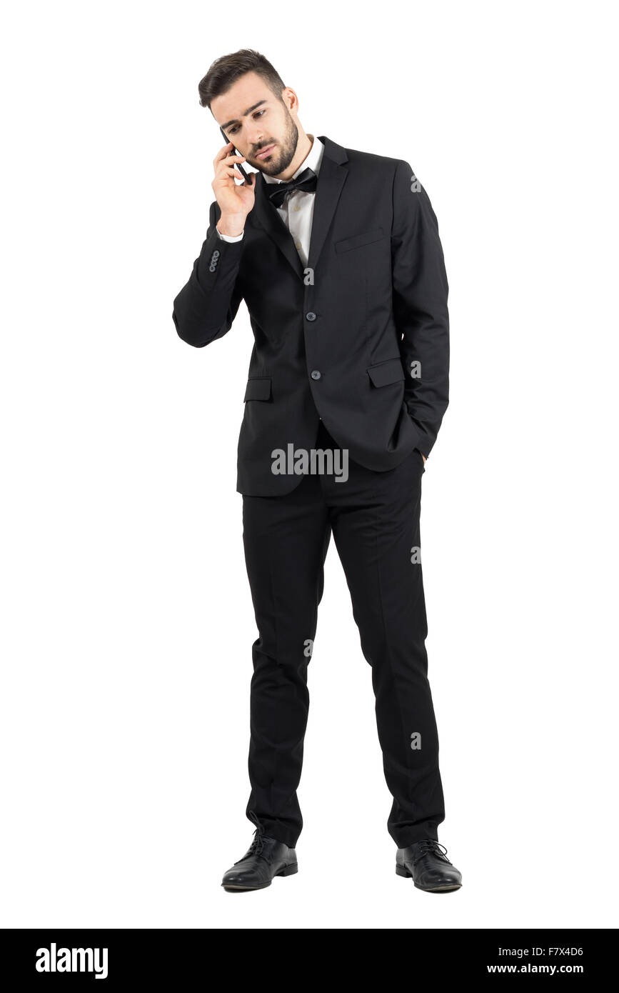 Sad young man in suit talking on the phone looking down. Full body ...